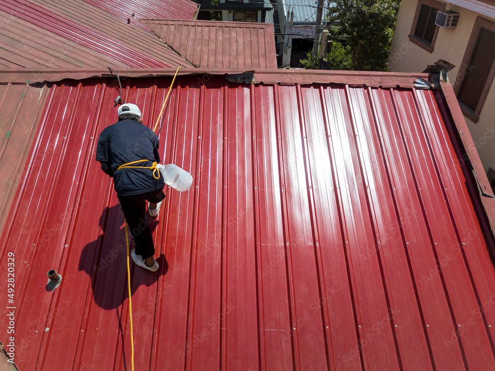 A roofing contractor installs new corrugated metal roofing with ribbed ...