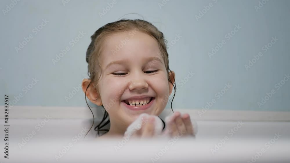 Portrait. European Cute girl preschooler takes a bath with foam, plays ...