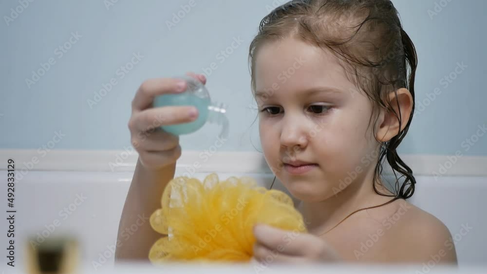 a teenage girl in the bath pours baby shampoo from a bottle onto a ...