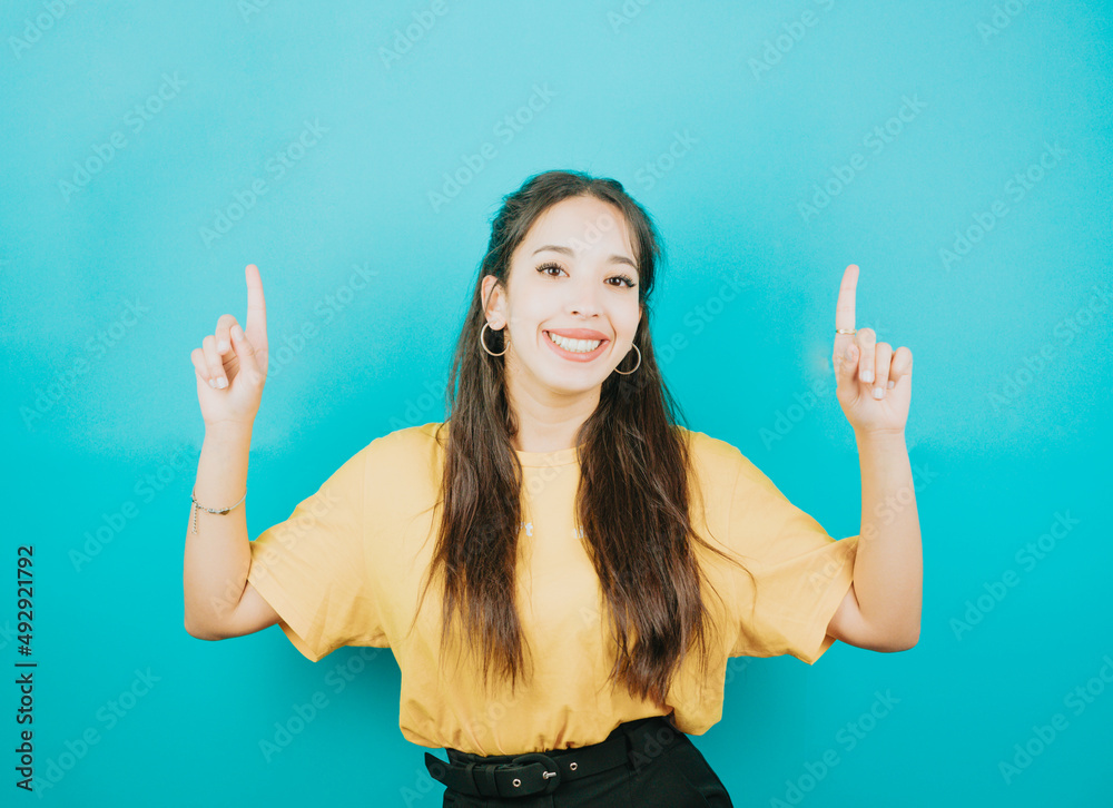 Young woman pointing copy space over his head for text and image. Blue ...