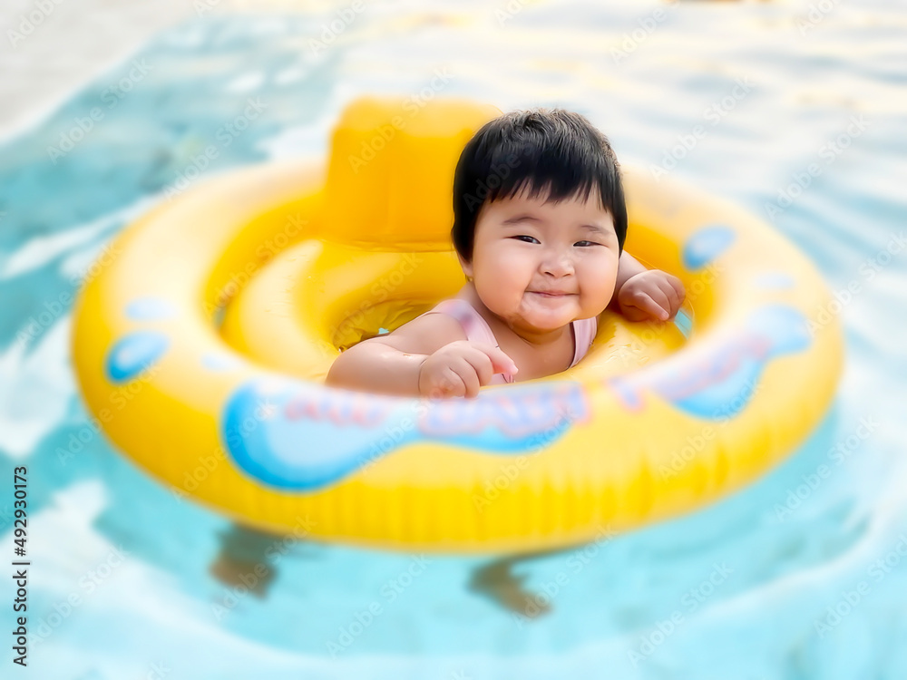 Happy cute little baby child learning to swim with swimming ring in an ...