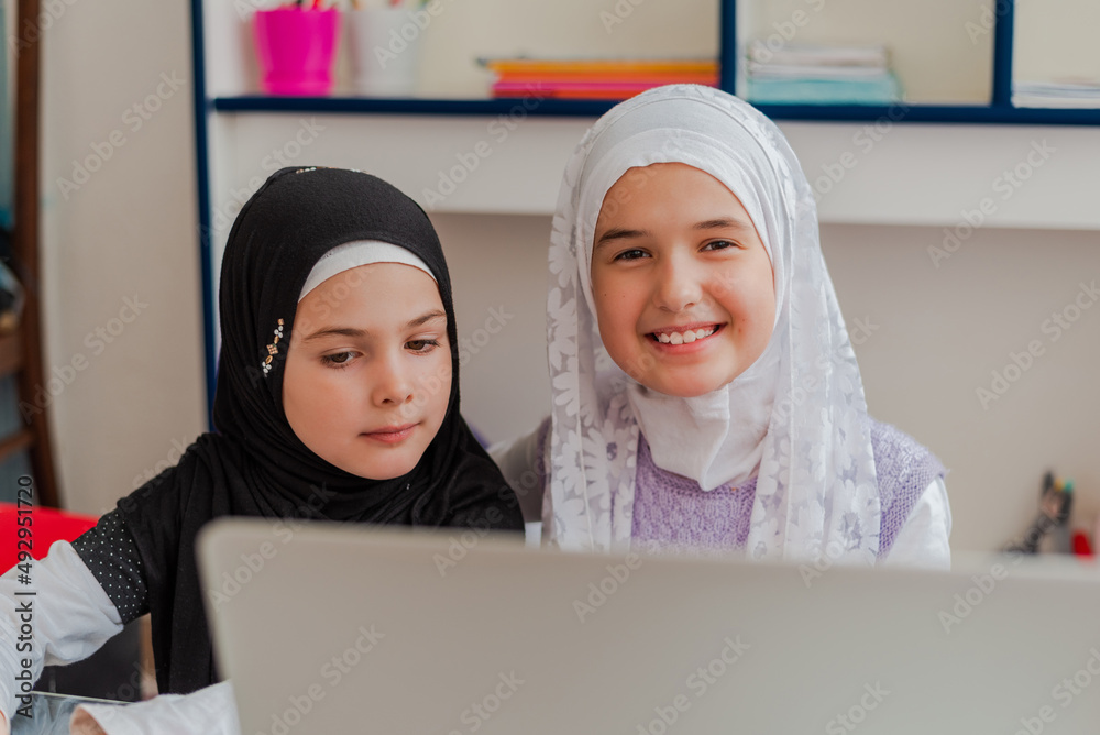 Two Muslim girls student learning for school on laptop in the home ...