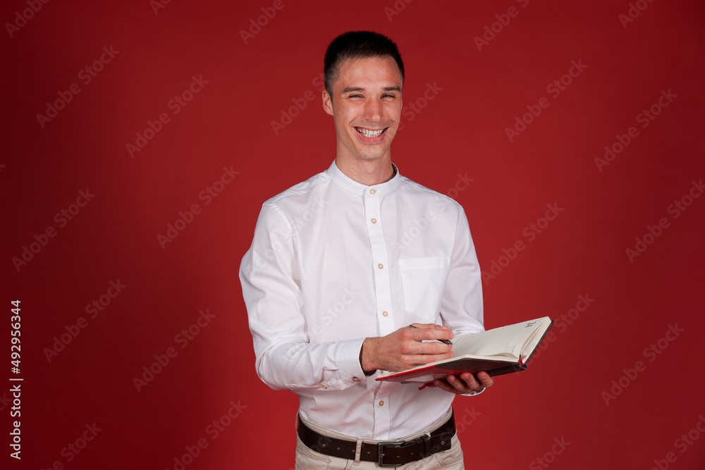 Happy businessman smiling and writing in notepad with pen while wearing ...