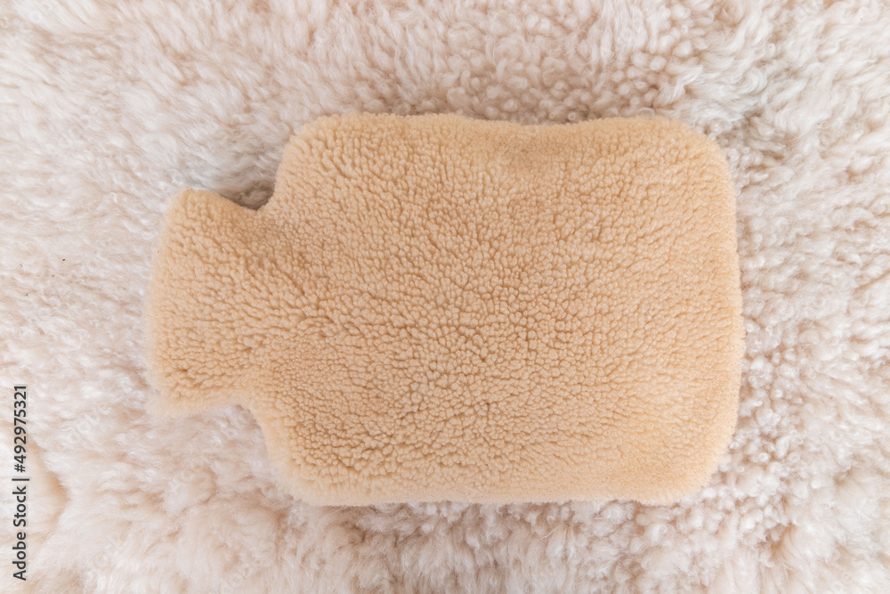 Colorful hot water bag standing on animal skin. There is an animal hide ...