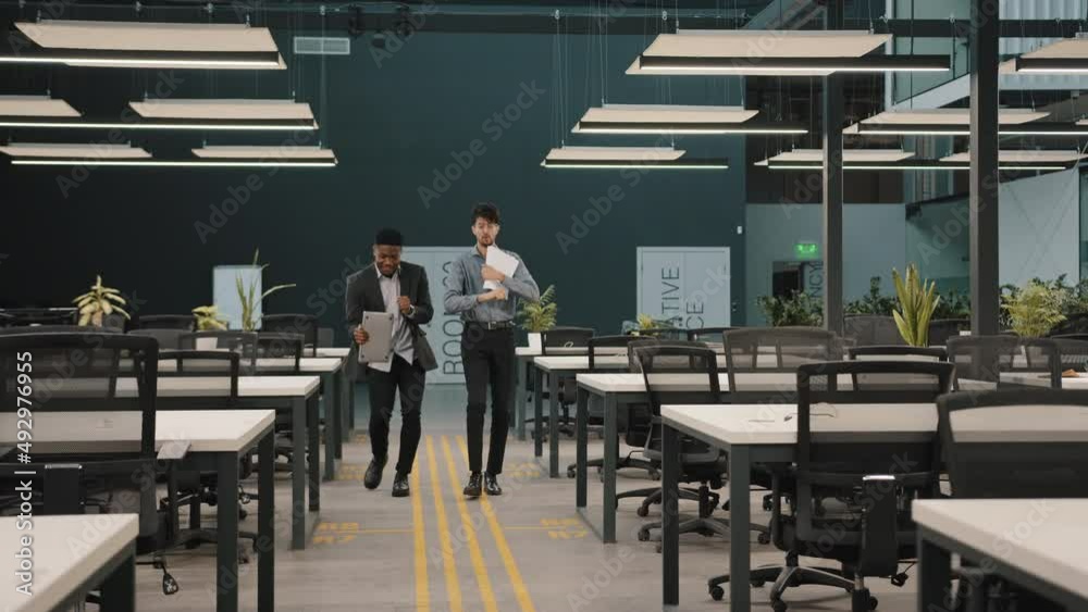 Overjoyed Arab professional male worker African man employee dancing in ...