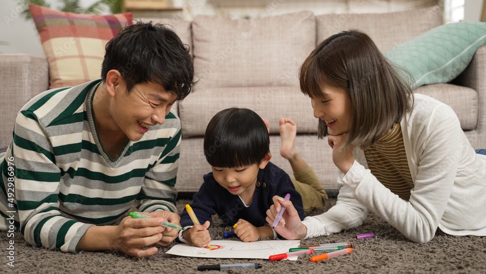 cheerful chinese family of three having fun lying prone on living room ...
