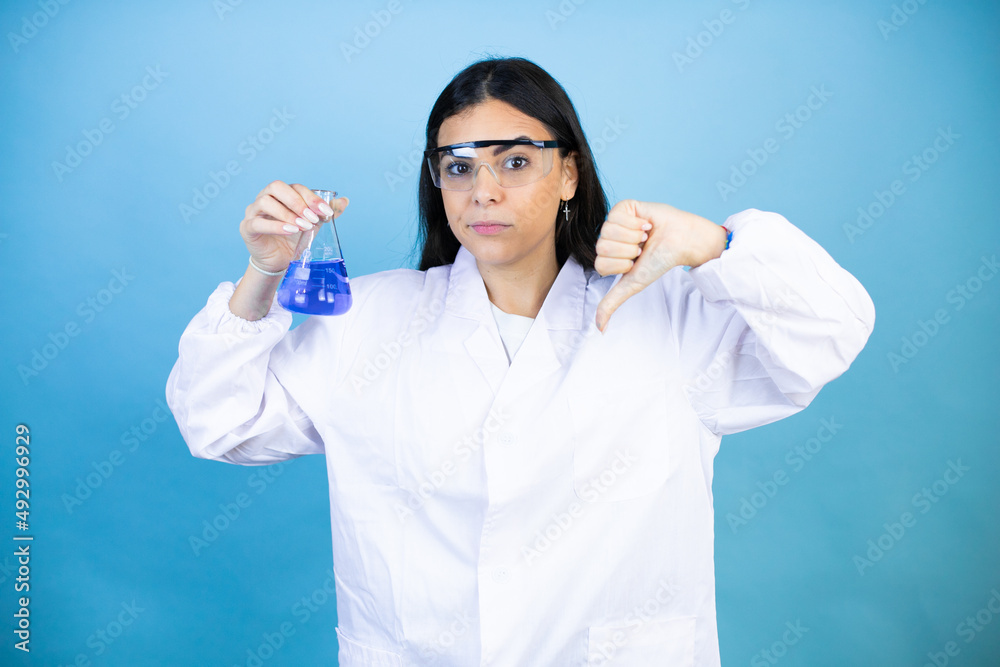 Young brunette woman wearing scientist uniform holding test tube over ...