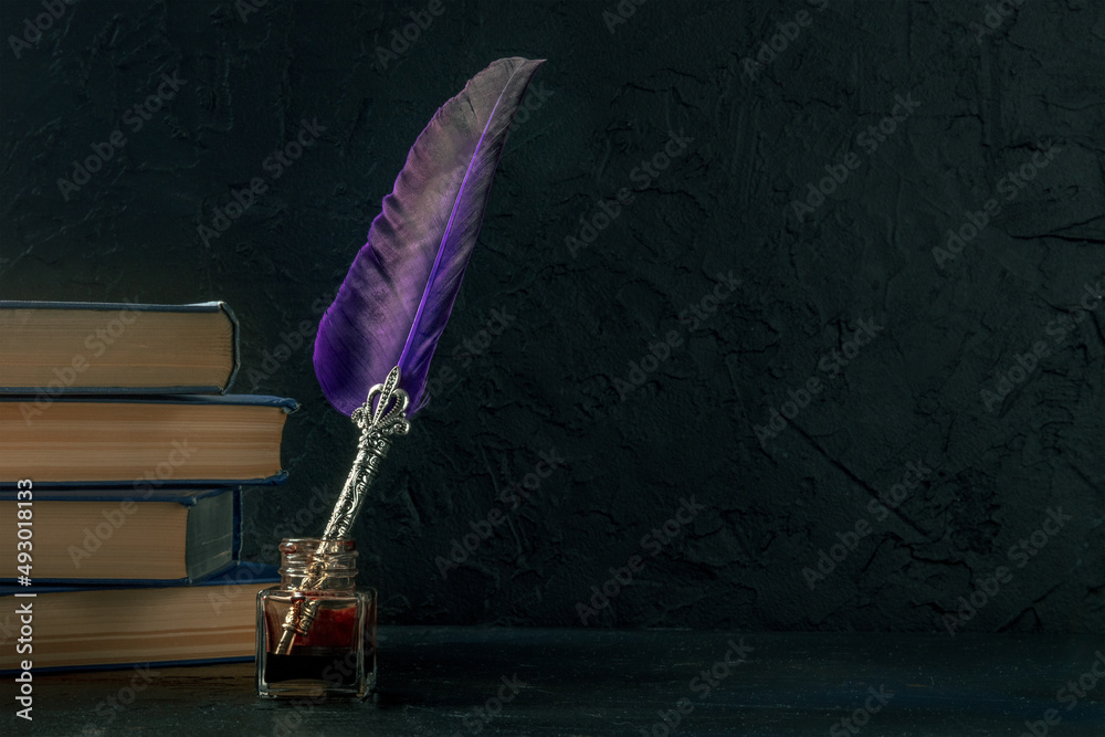 Quill pen with a retro ink well and a stack of old books, a side view ...