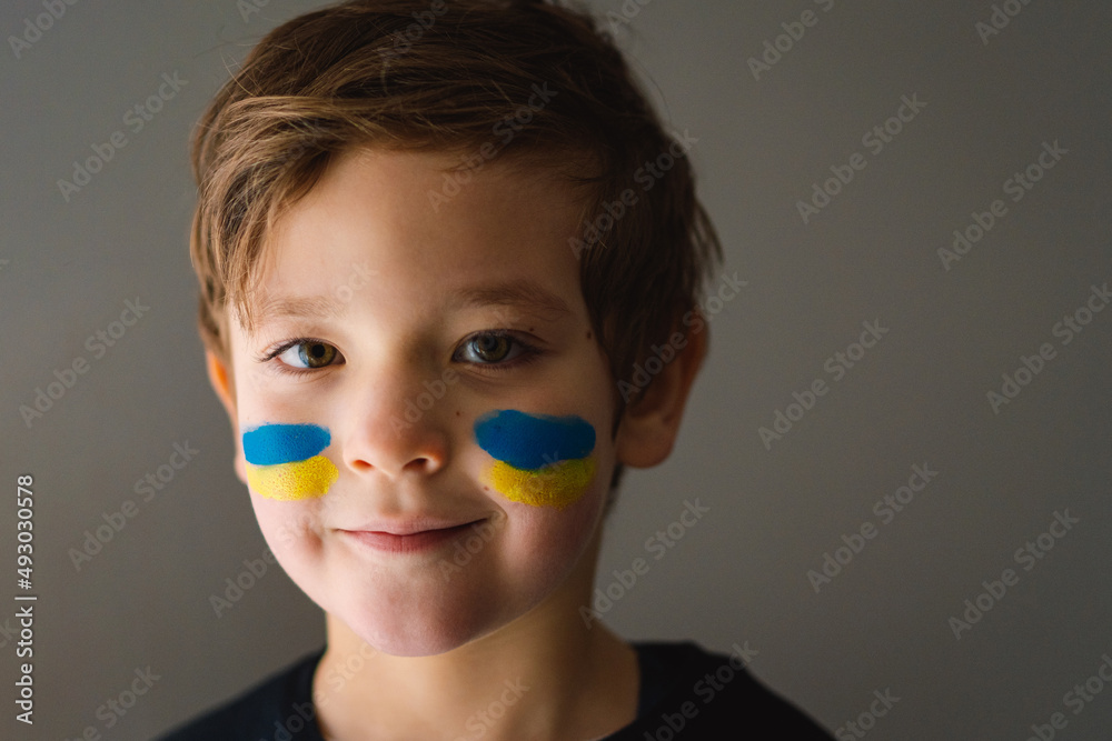 Portrait of a Ukrainian boy with a face painted with the colors of the ...