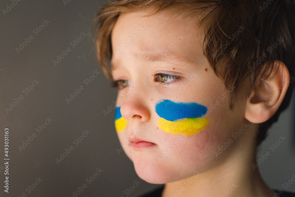 Portrait of a Ukrainian boy with a face painted with the colors of the ...
