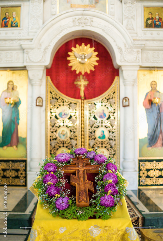 Crucifixion week. A cross decorated with flowers lies on a lectern in ...