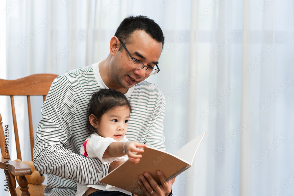 Asian father reading storybook to daughter in living room, family ...