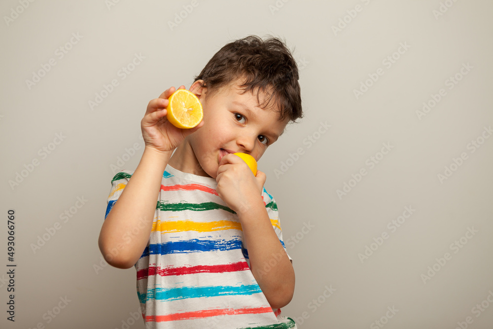 little boy eating lemon, sour taste, makes grimace, facial emotions ...