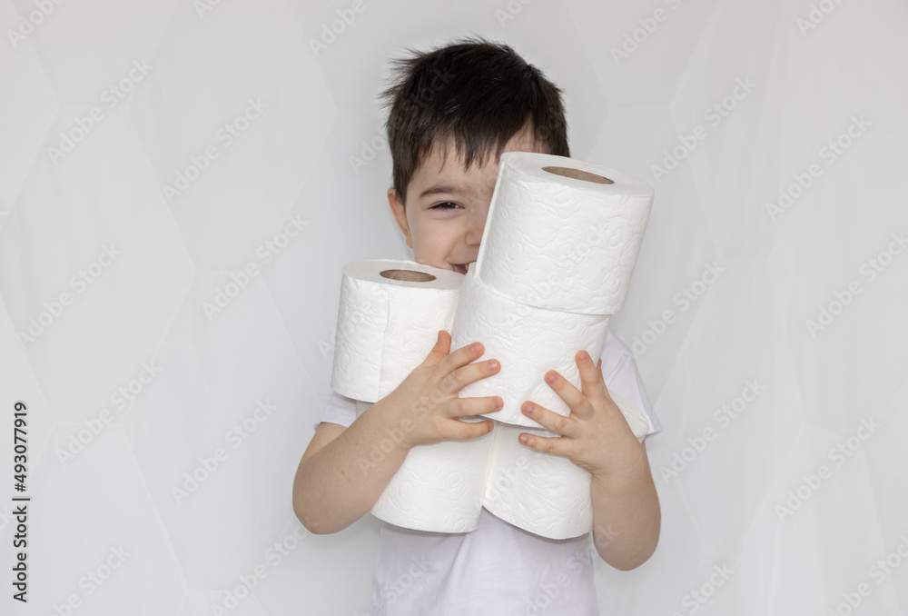 cute little boy is holding toilet paper rolls in arms, or is looking ...