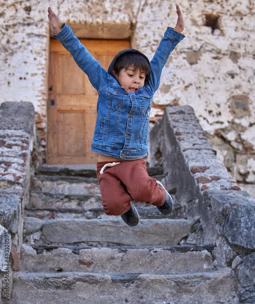 child jumping for joy on an old staircase in an Argentinian village ...