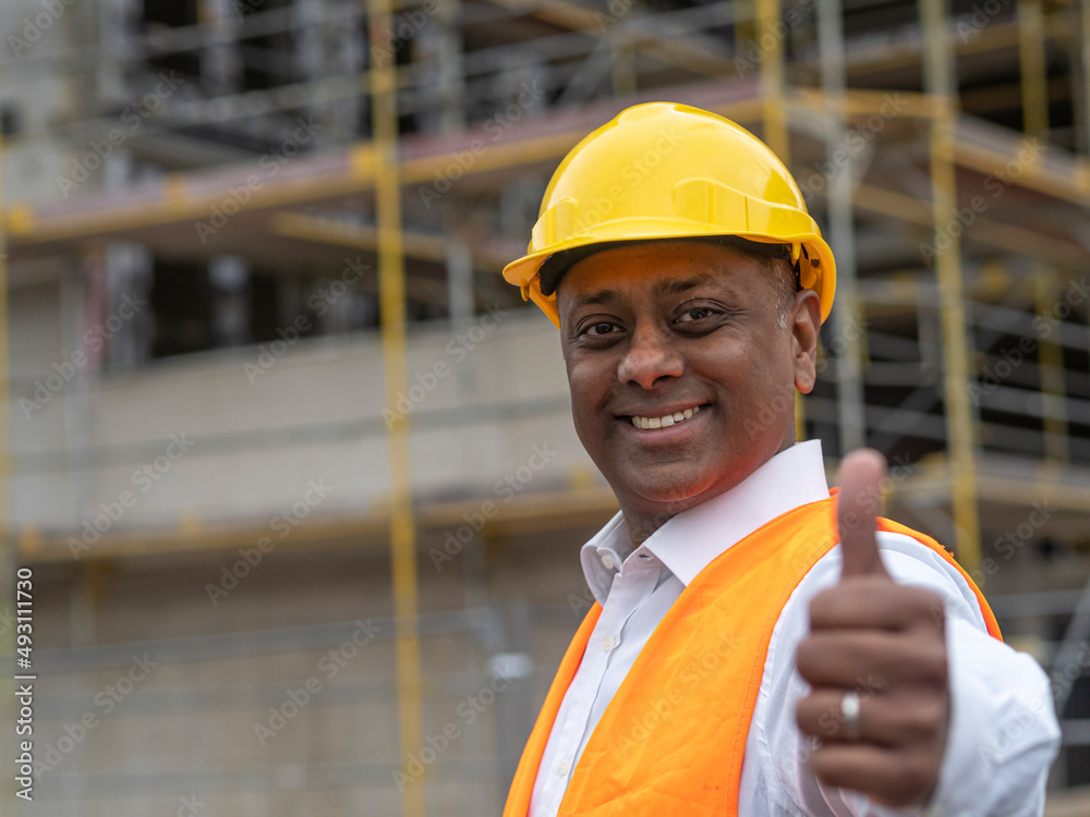 Positive, smiling and successful Indian construction worker posing ...