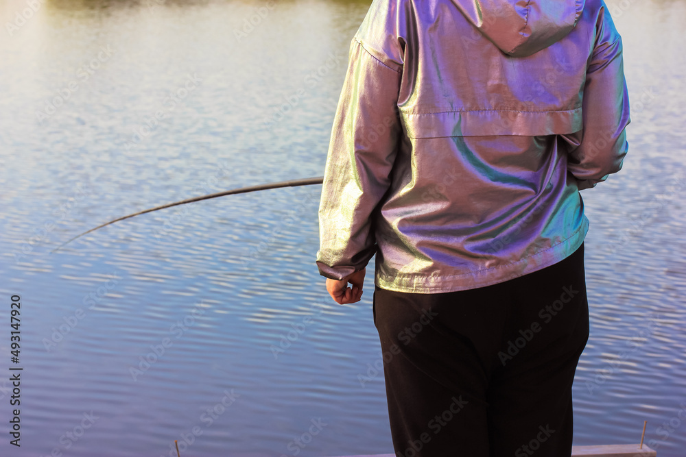 Fotografia do Stock: Fisherwoman with a yellow fishing rod by a pond ...