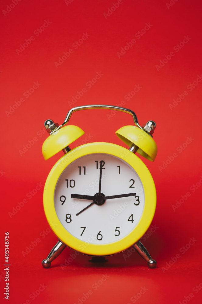 Bright yellow retro alarm clock isolated on paper red background. Time ...