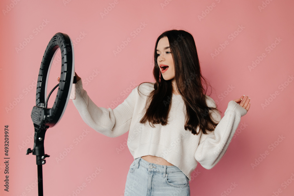 Foto de Beautiful young woman is adjusting a mobile phone to the ring ...