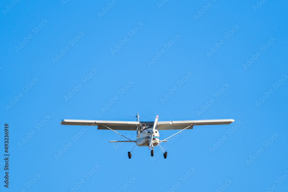 Small plane flying head-on in a clear blue sky Stock Photo | Adobe Stock