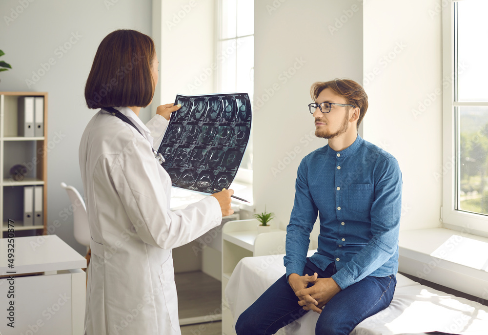 Female doctor in modern clinic gives young man his X ray image ...