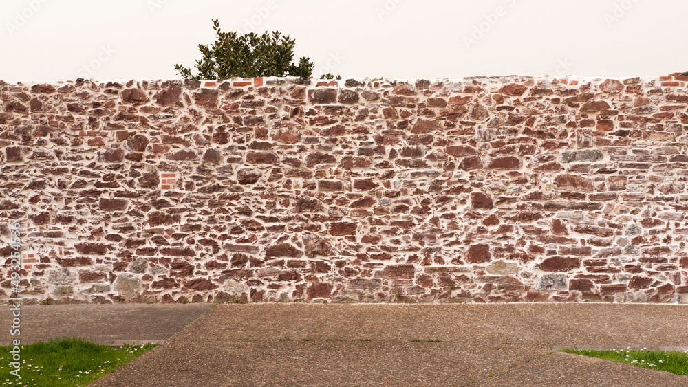 Muro de piedra rocosa rojiza en centro de pueblo europeo Stock Photo ...