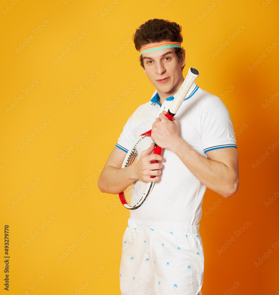 How do you hold this again. A young man in a retro tennis outfit holding his racket like a ...