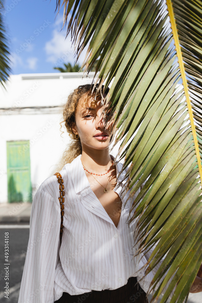 Portrait of girl hidden behind a palm leaf Stock Photo | Adobe Stock