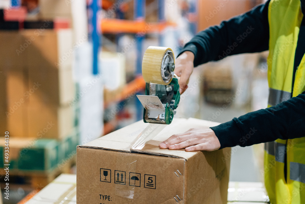 Anonymous worker sealing boxes with tape Stock Photo | Adobe Stock