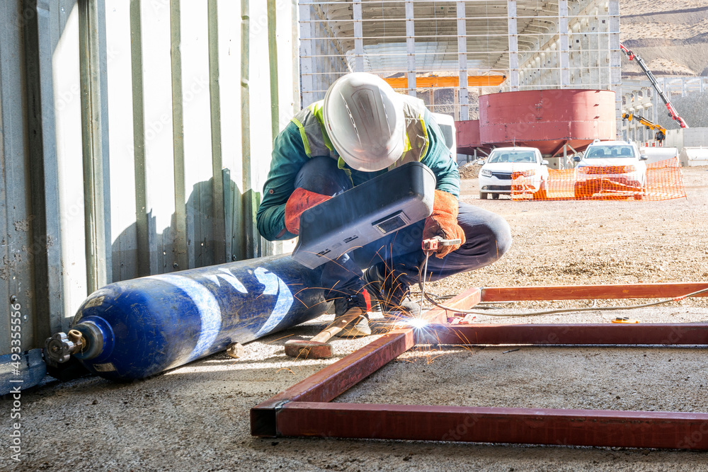 Welder is welding to steel material near to oxygen cylinder in the ...