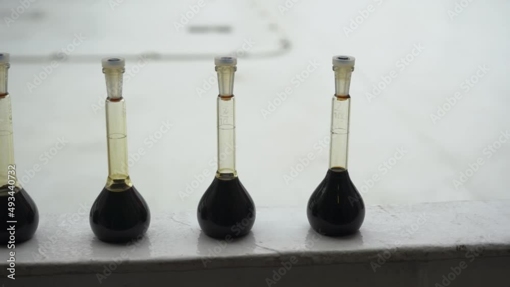 Oil in glass tubes. Test tubes with black oil. Dark liquid in flasks ...
