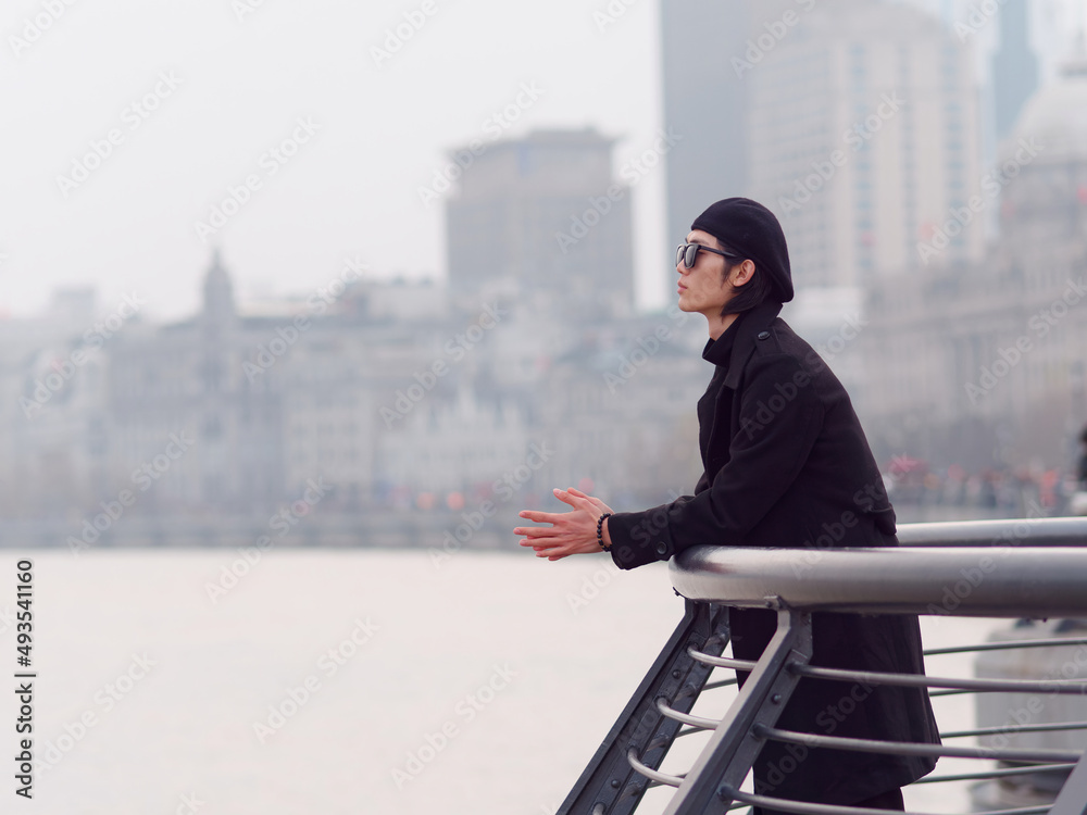 Portrait of handsome Chinese young man wearing black overcoat and ...