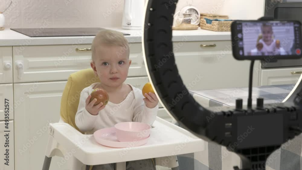 Parents record video on smartphone of kid in high chair at home ...