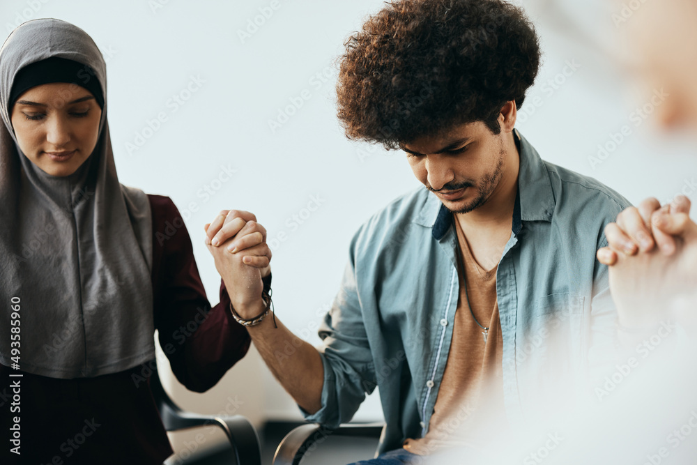 Muslim man holding hands with participants of group therapy during ...