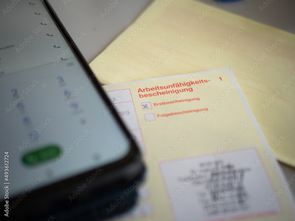 German sick certificate and smartphone with number pad: sick leave by ...