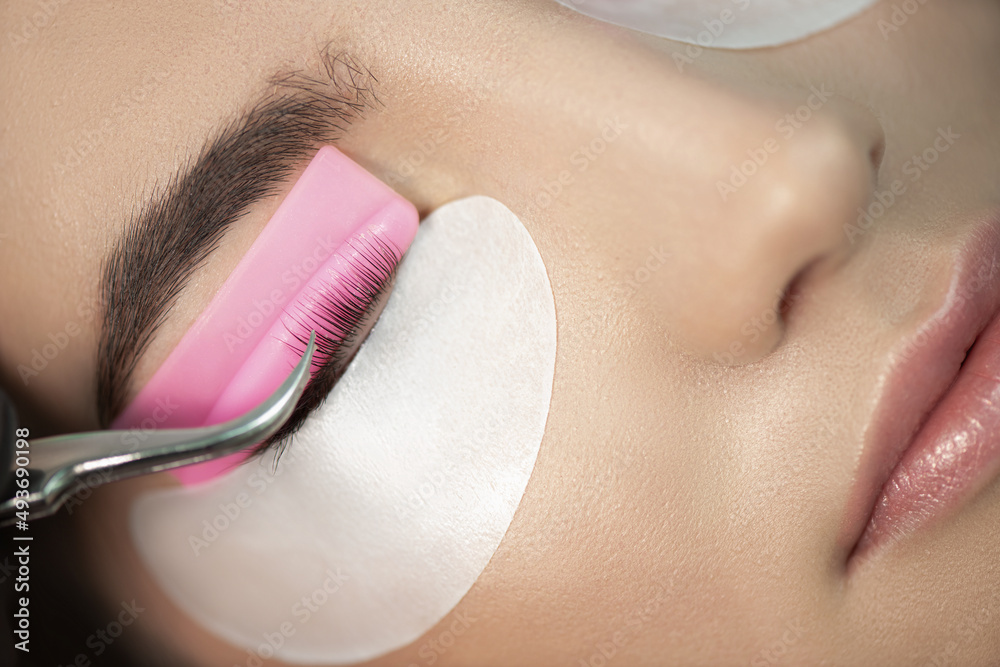 Foto de Master glues eyelashes to pink lash roller. Close-up of beauty ...