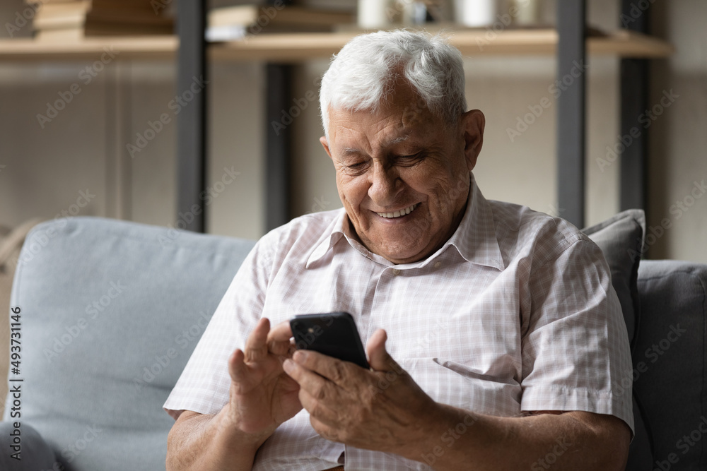 Stockfoto Happy elderly man look at cell phone screen rest on sofa at ...