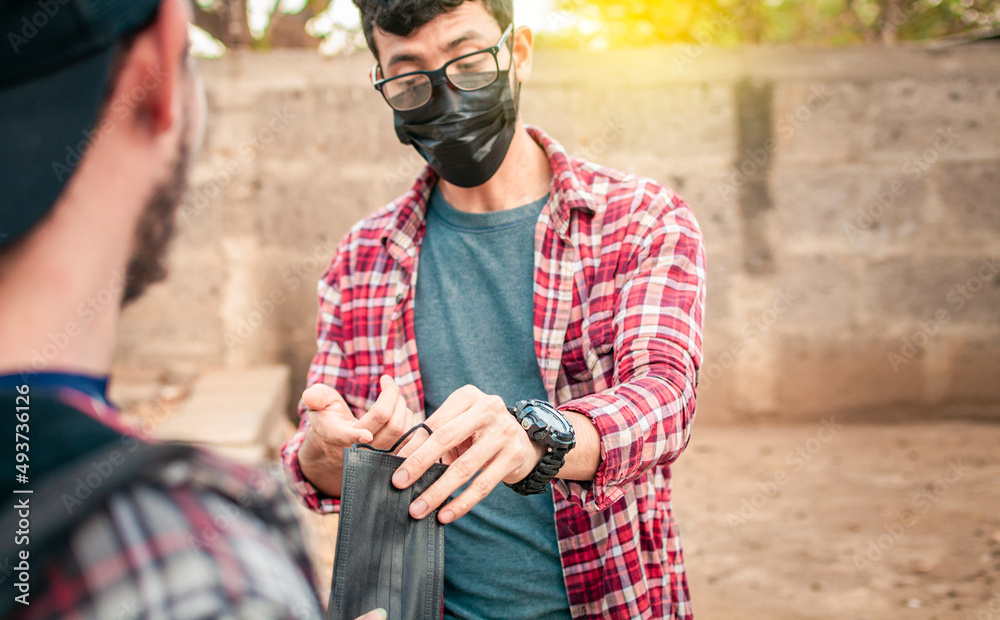 Two young people giving each other a mask, image of a young man giving ...