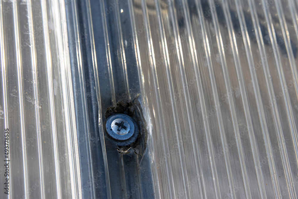 Close-up of incorrect fastening of a polycarbonate sheet. Damaged ...