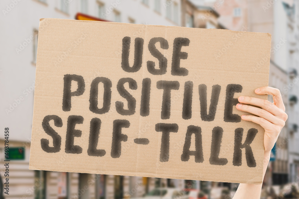 The phrase " Use Positive Self-Talk " on a banner in men's hands with ...