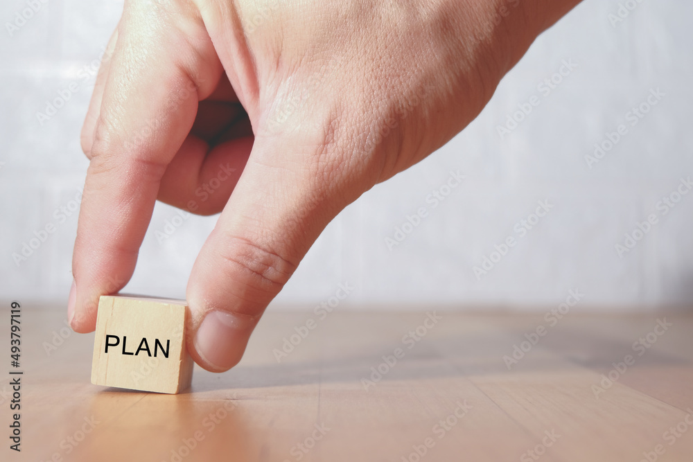 Hand put the wooden cute block with the wording PLAN on the wooden ...