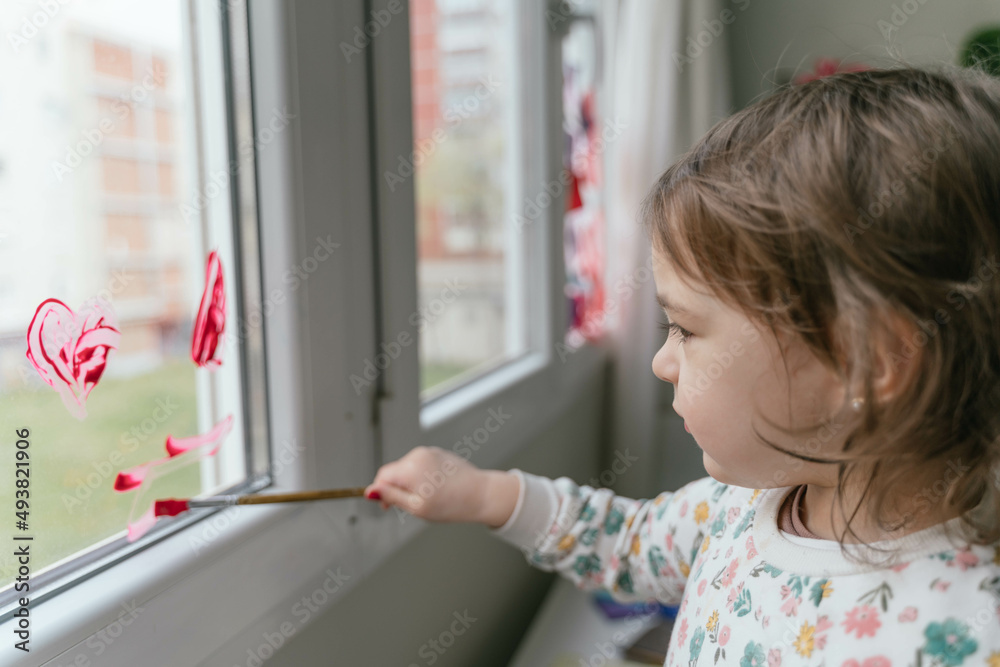 Adorable little girl painting a window Stock Photo | Adobe Stock