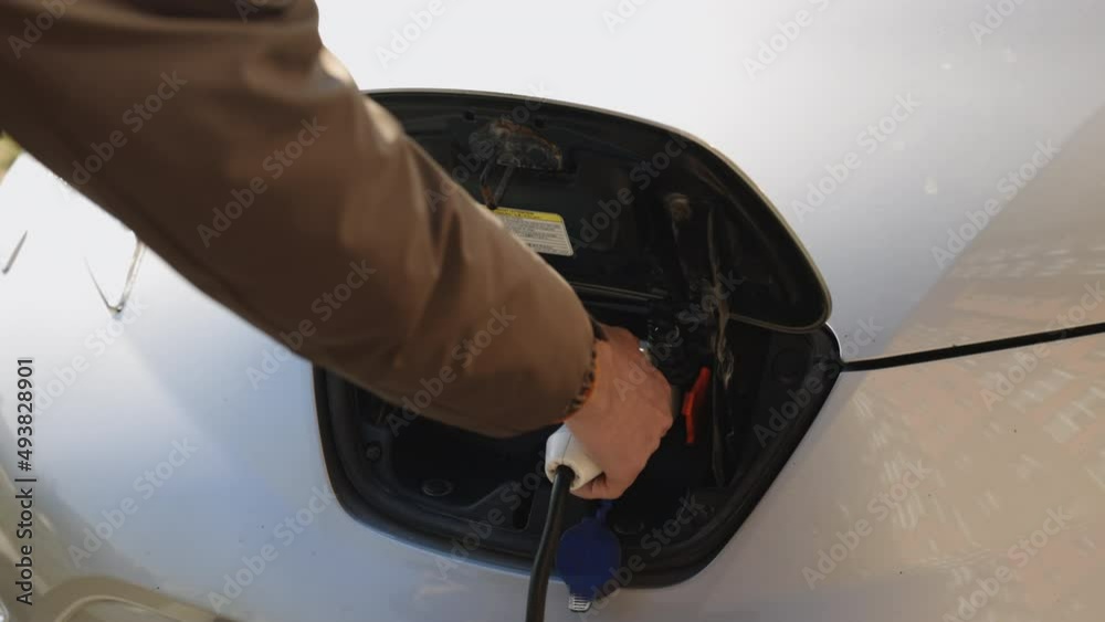 Unrecognizable man disconnects charging cable to electric vehicle. Male ...