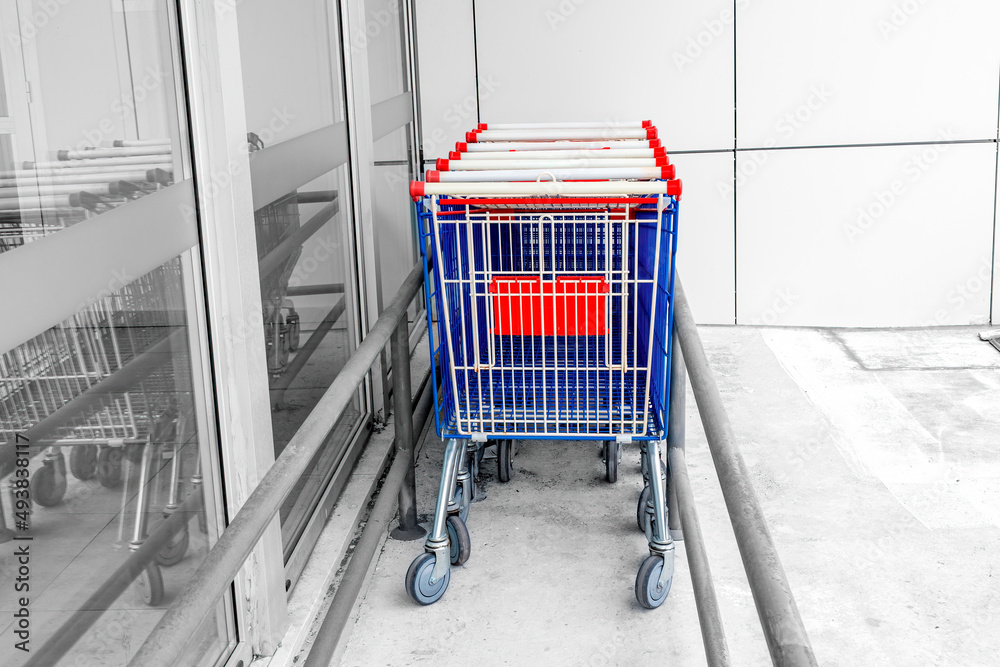 Blue carts are parked at the entrance to the supermarket. Shopping ...