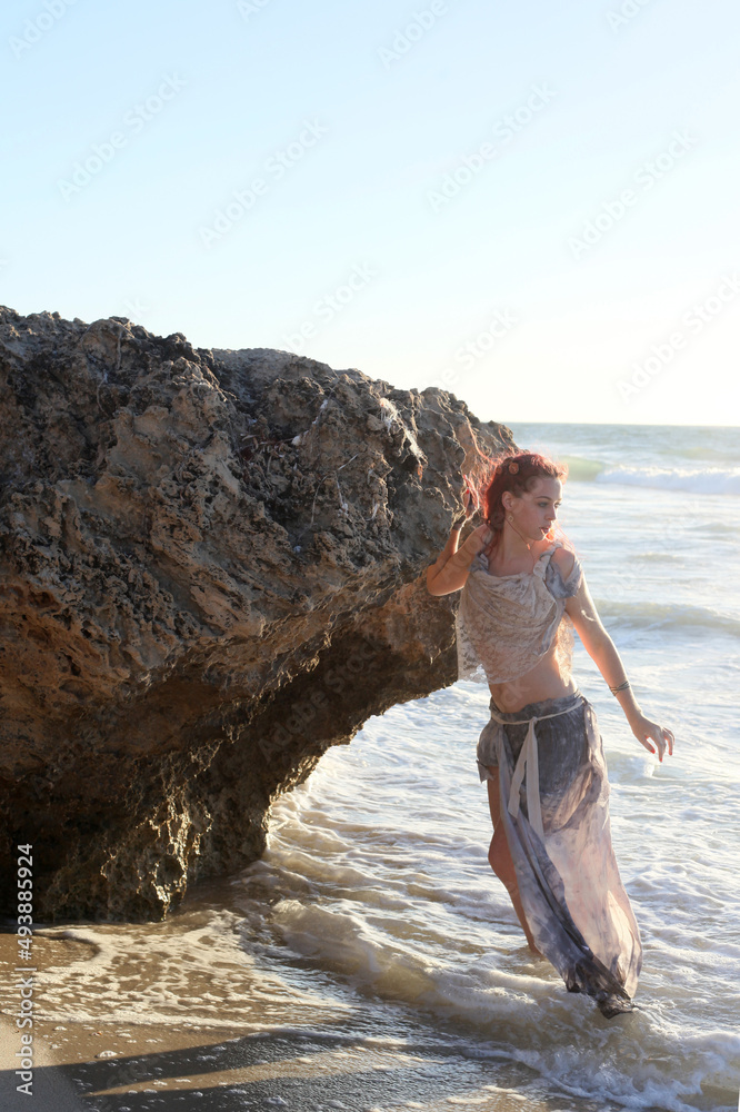 Full length portrait of red haired woman wearing torn shipwrecked ...