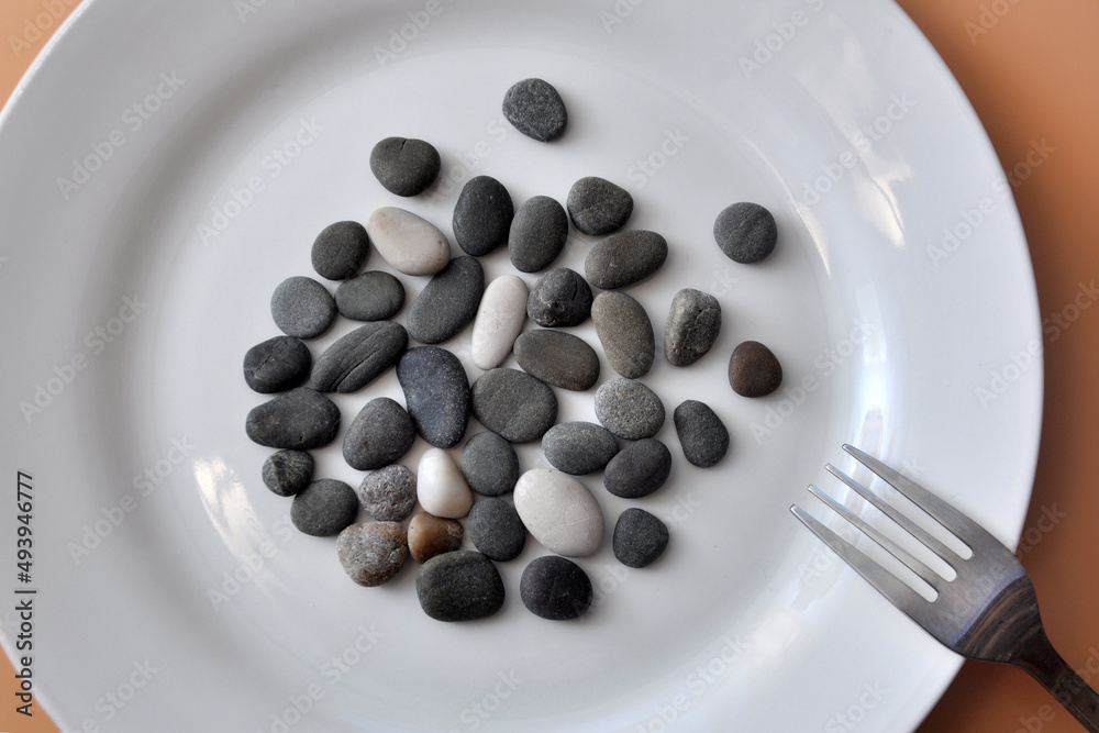 Stones on a plate. A symbol of heavy, unhealthy food. Heaviness in the ...