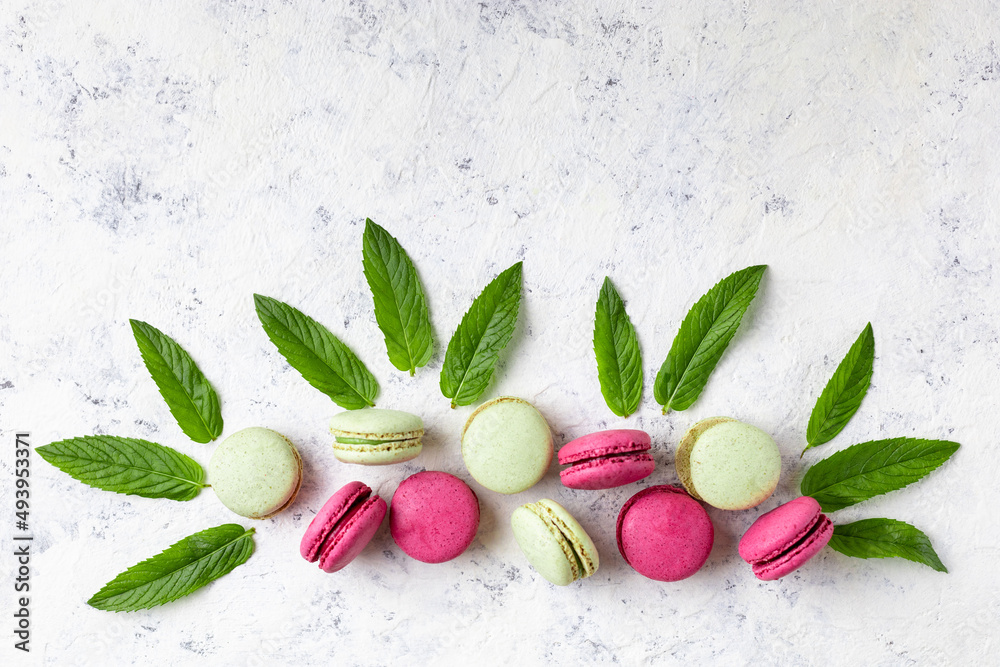 Design of green and pink macarons with mint leaves on white background ...
