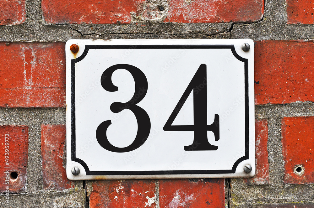 Sign of a street number 34 on a red brick wall Stock Photo | Adobe Stock