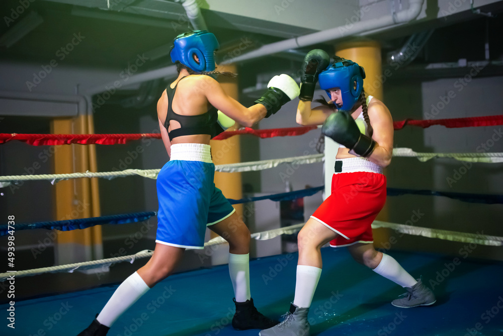 Sporty female boxers boxing in gym. Two trained girls in helmets and ...