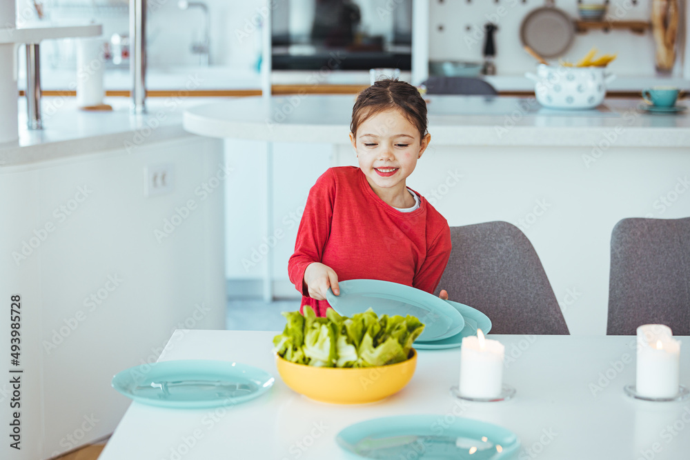 Happylittle girl setting the table for family lunch during holidays ...